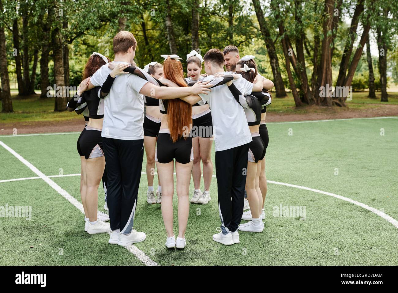 Cheerleader team standing together in circle outdoors and talking to ...