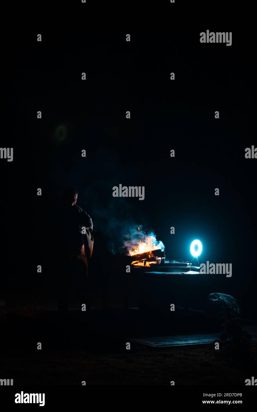 Man preparing bbq grill to cook on fire. Outside dark shot. Freeze ...