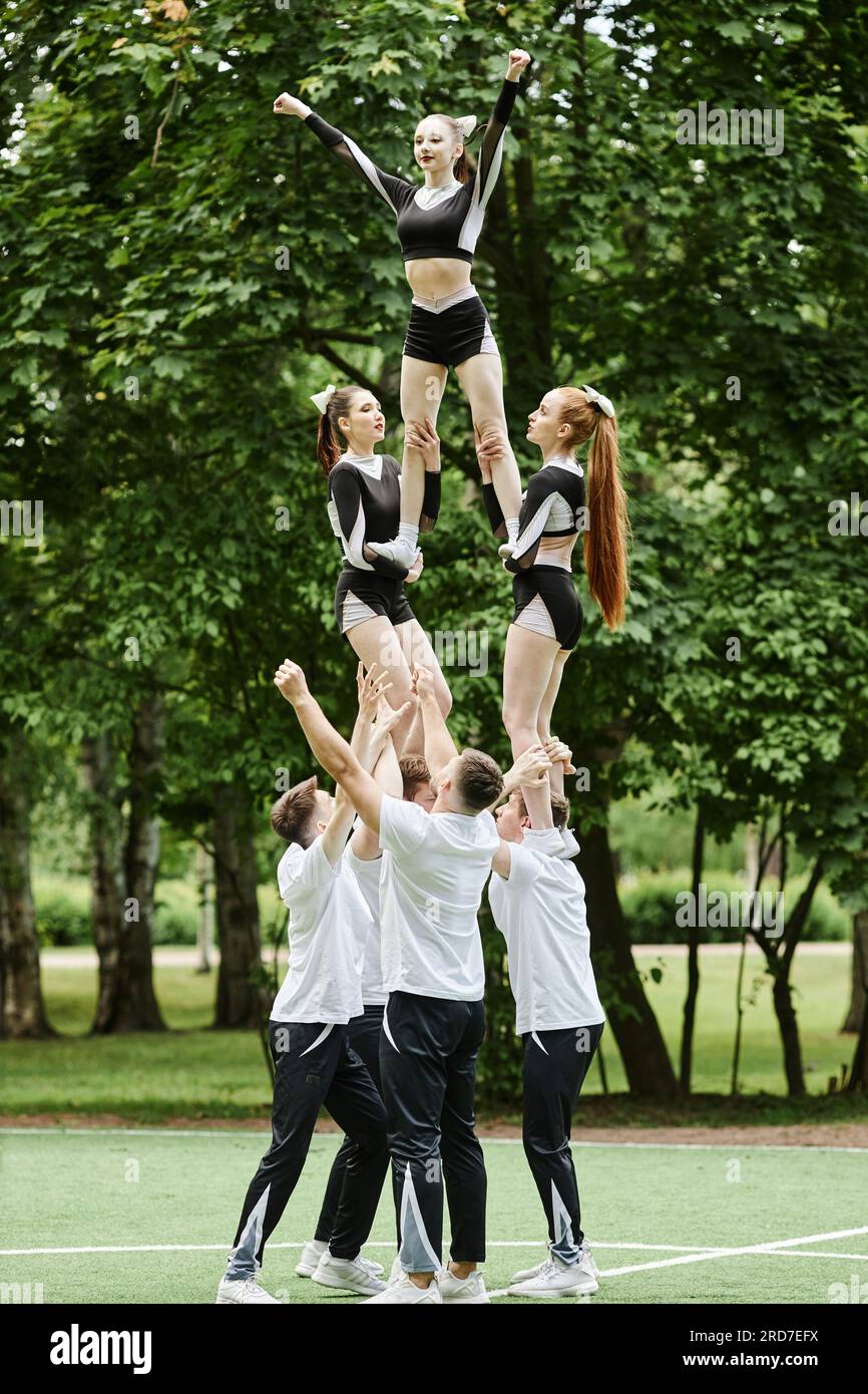 Vertical image of cheerleader team performing together outdoors, they ...