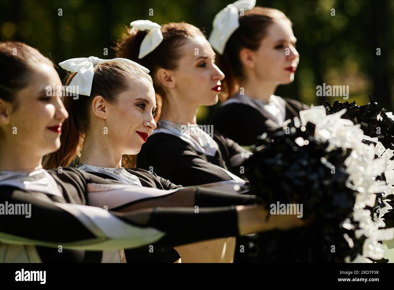 Group of beautiful cheerleading girls with pompom training outdoors ...