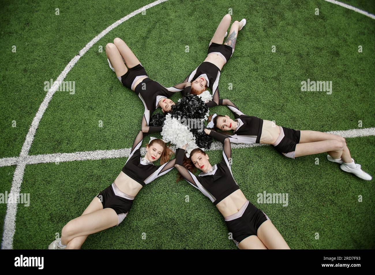 Top view of group of cheerleading girls with pompom posing on grass of ...