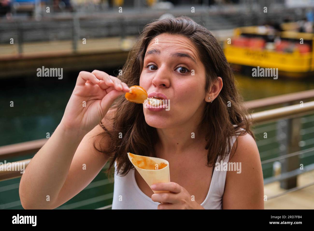 Tourist eating mitarashi dango and looking at camera at street Stock ...