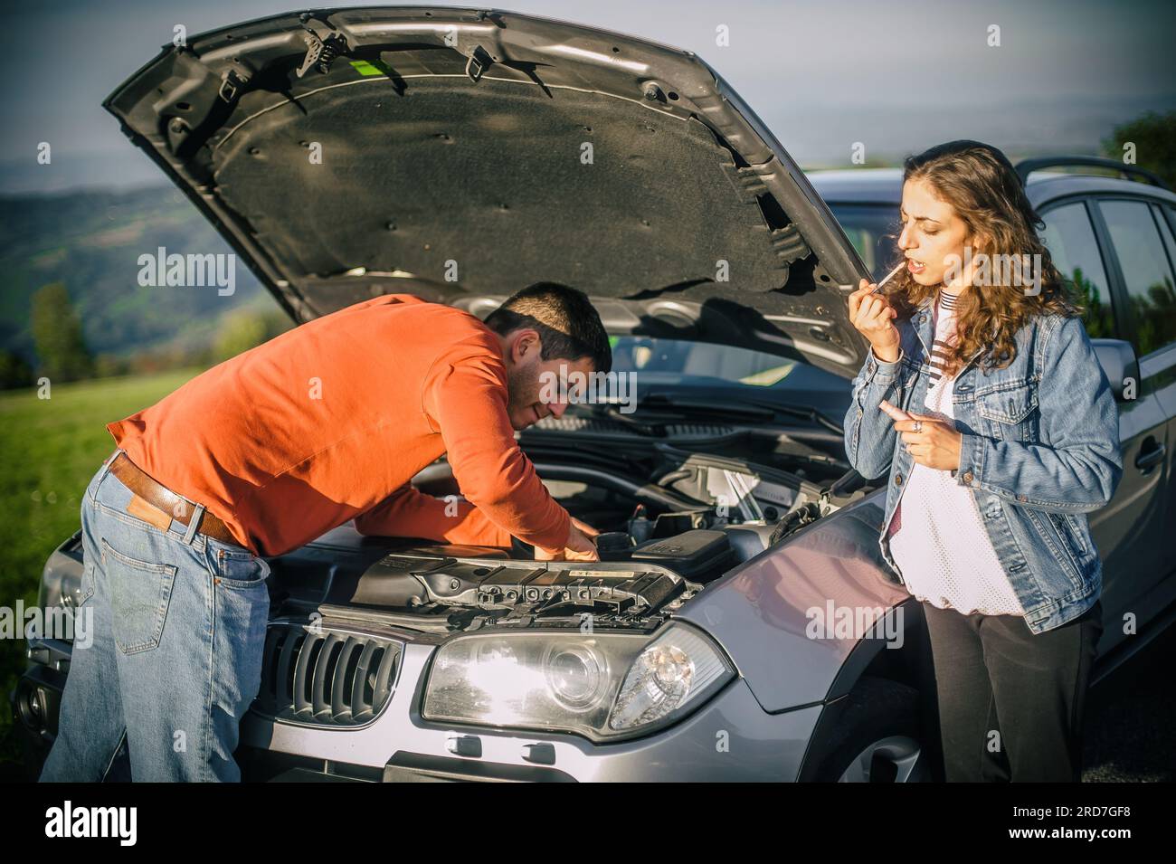 Funny scenario. A young couples car breakdown. The young man is trying ...