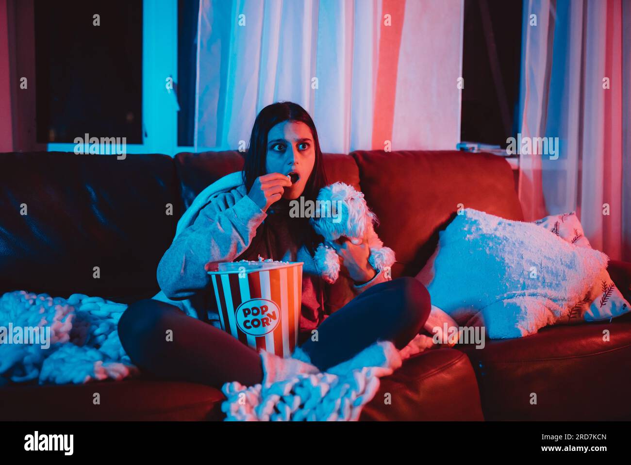 Beautiful young girl watching movie at home in a dark room with a ...