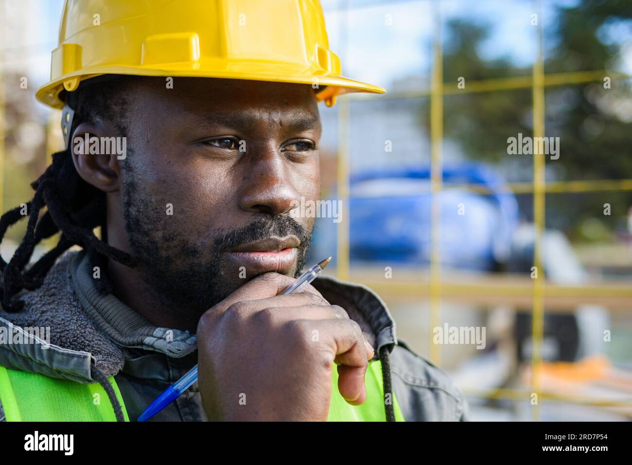 closeup portrait of black engineer man wearing safety helmet outdoors at construction site ...