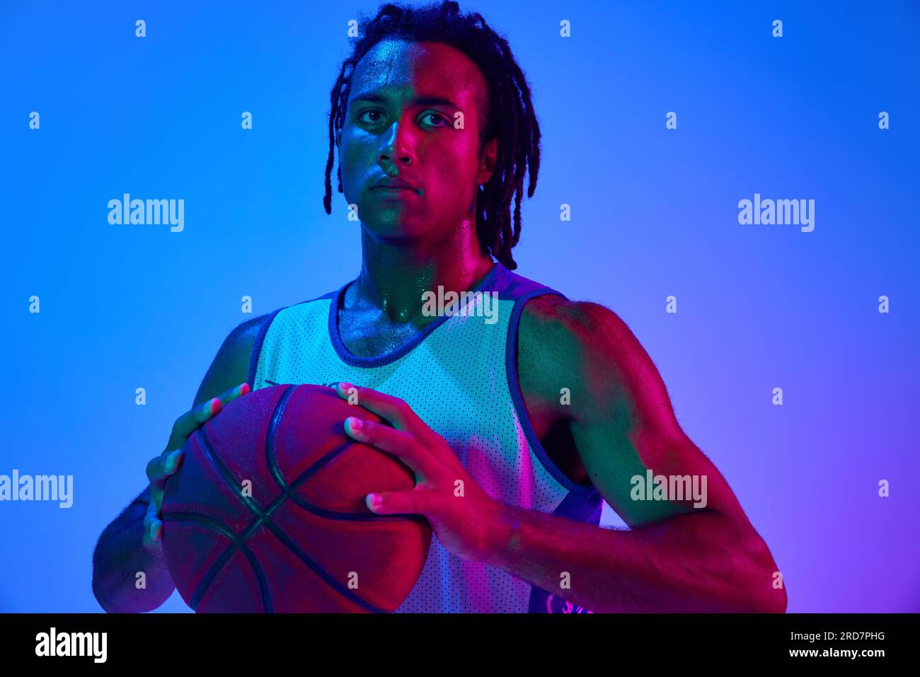 Young man with dreads, basketball player in uniforma posing with ball ...