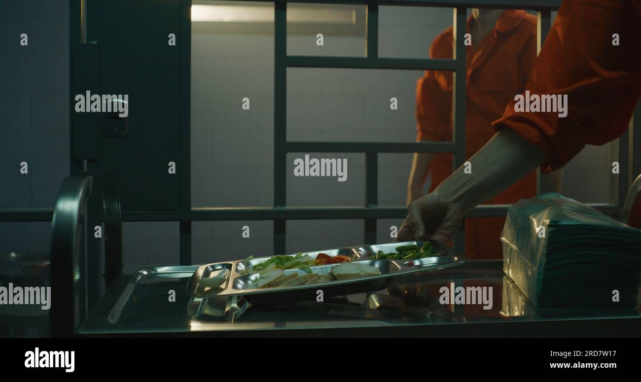 Prison Worker Gives Food From Serving Trolley To Female Prisoner In Orange Uniform In Jail Cell 1950