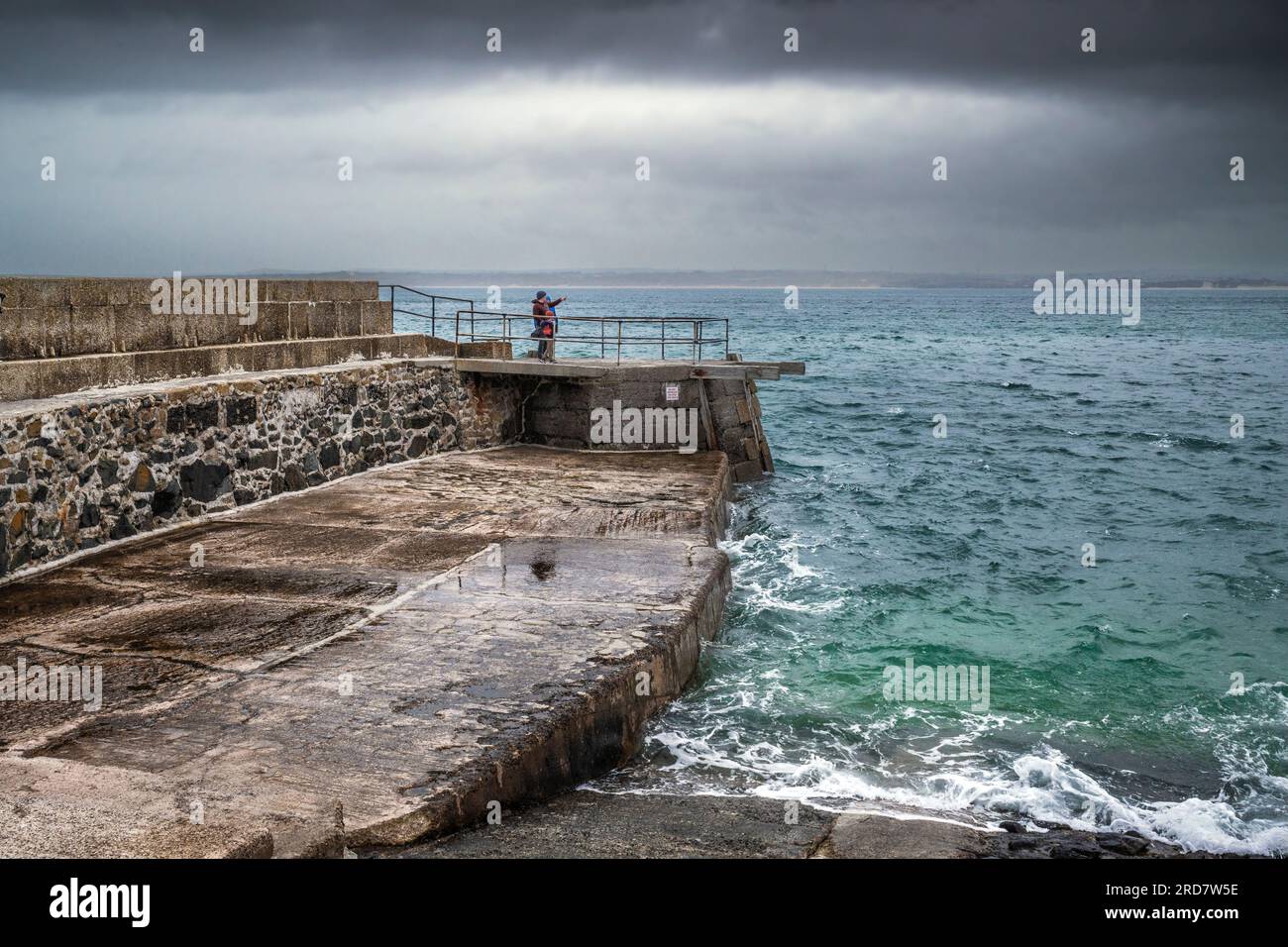 UK weather. Visitors standing on The Wharf on a rainy chilly miserable ...
