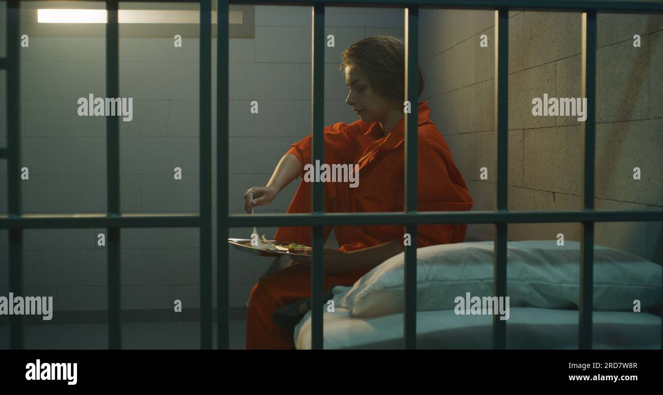 Prisoner in orange uniform gives dinner from food serving trolley to ...