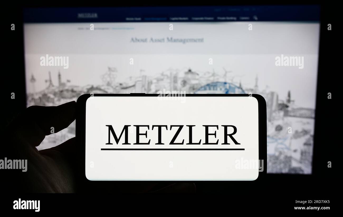 Person holding mobile phone with logo of banking company B. Metzler ...