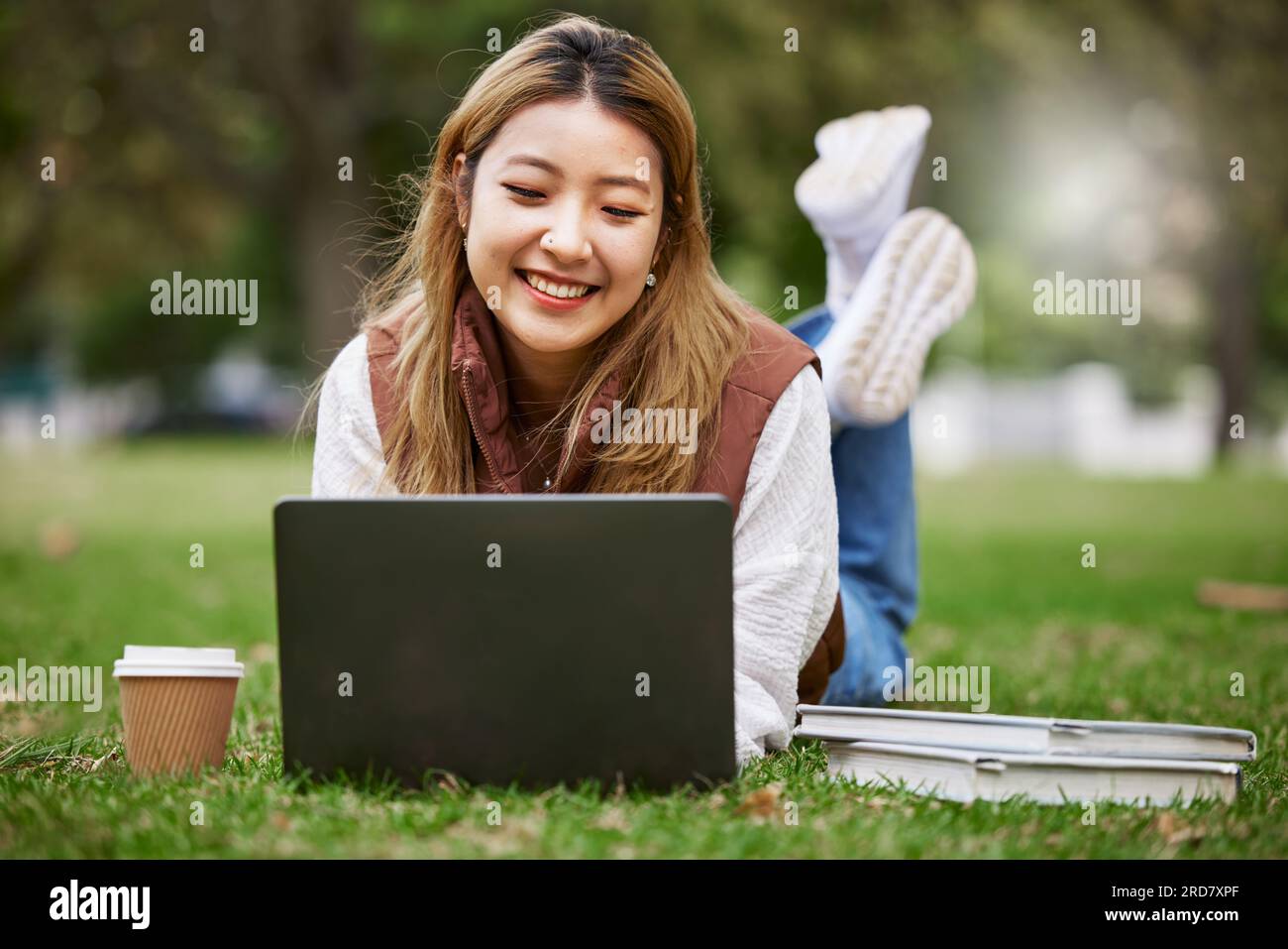 Laptop, asian and woman student typing in a park to update social media ...