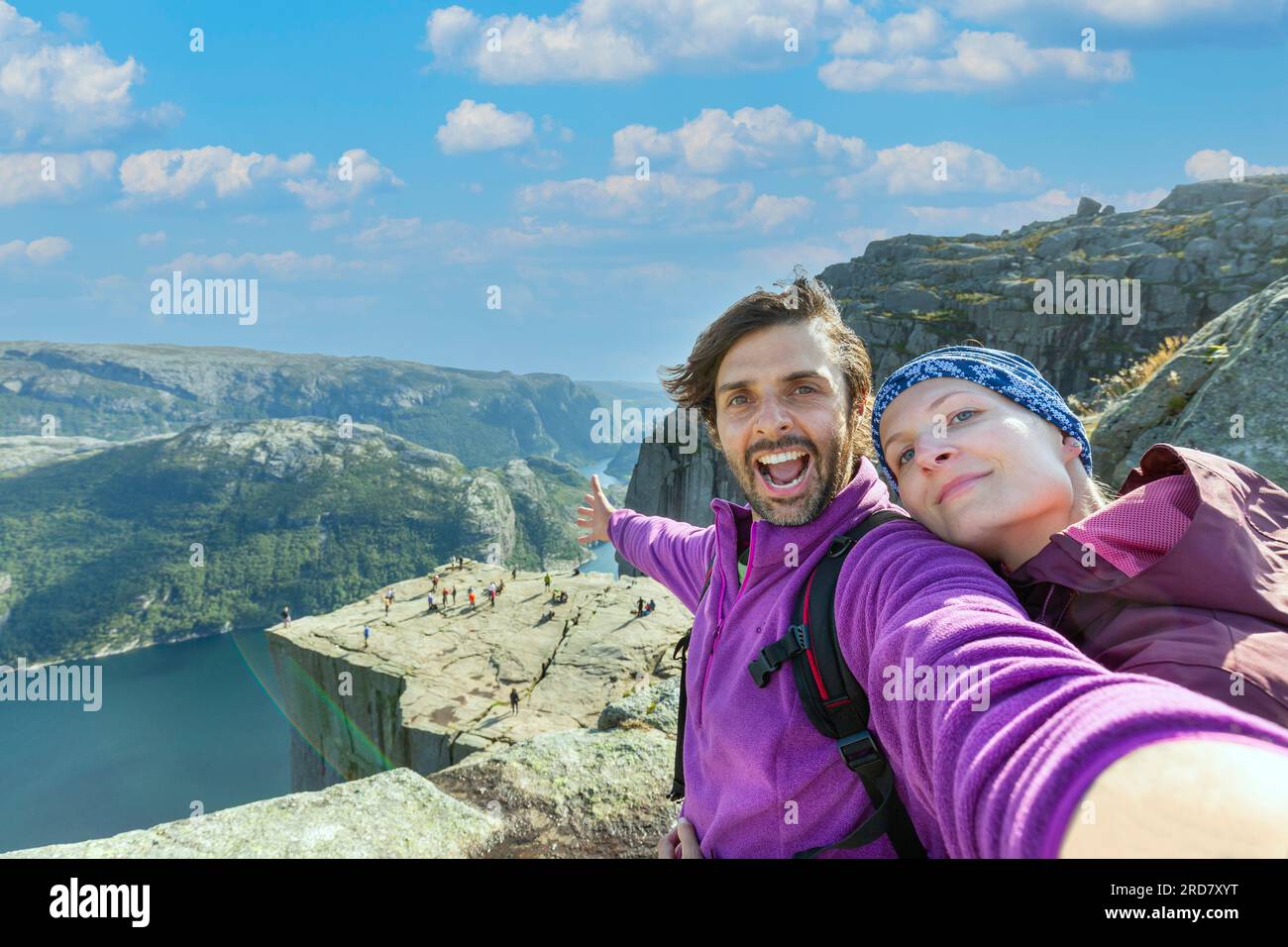 Couple taking a selfie on a rock and admiring a view on Preikestolen ...
