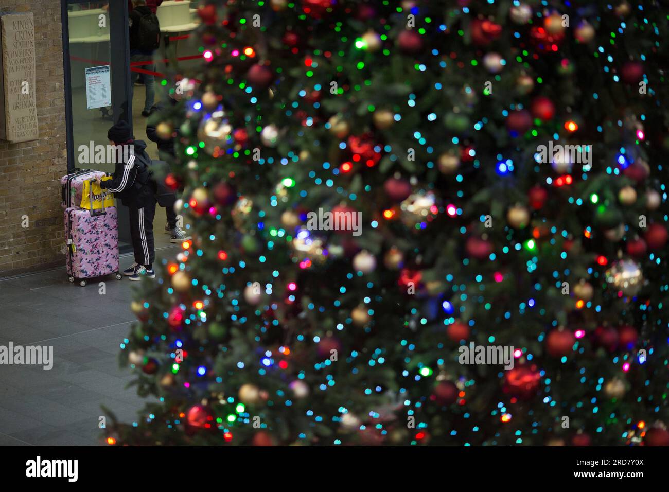 People walk past a Christmas tree at King Cross Station in London Stock ...