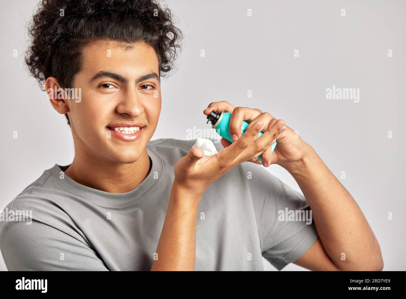 Happy young smiling guy putting facial wash on his fingers, preparing ...