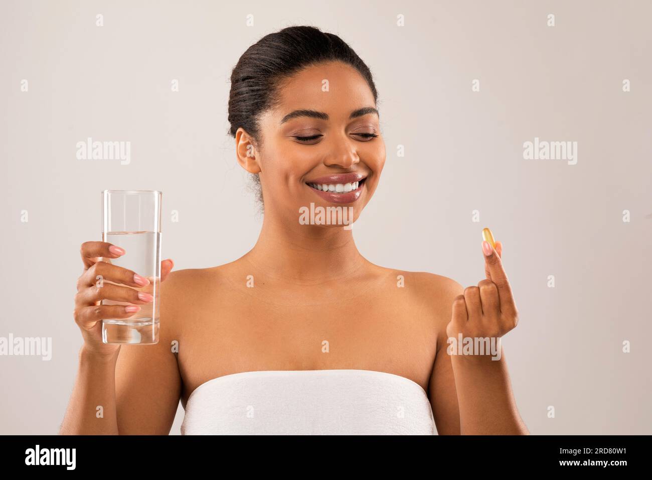 Beautiful young black woman taking beauty pill, grey background Stock ...