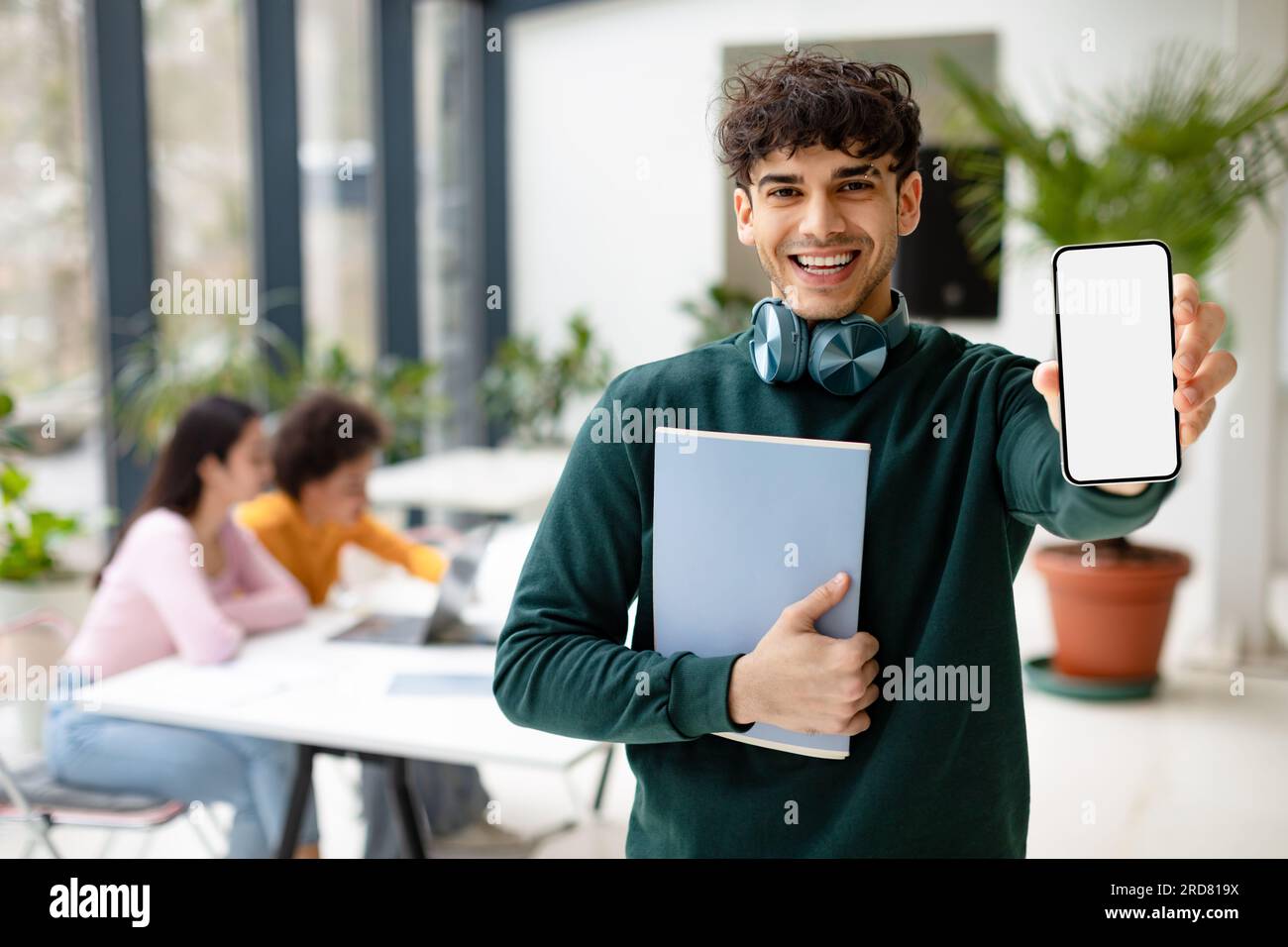 Positive european student guy showing smartphone with blank screen ...