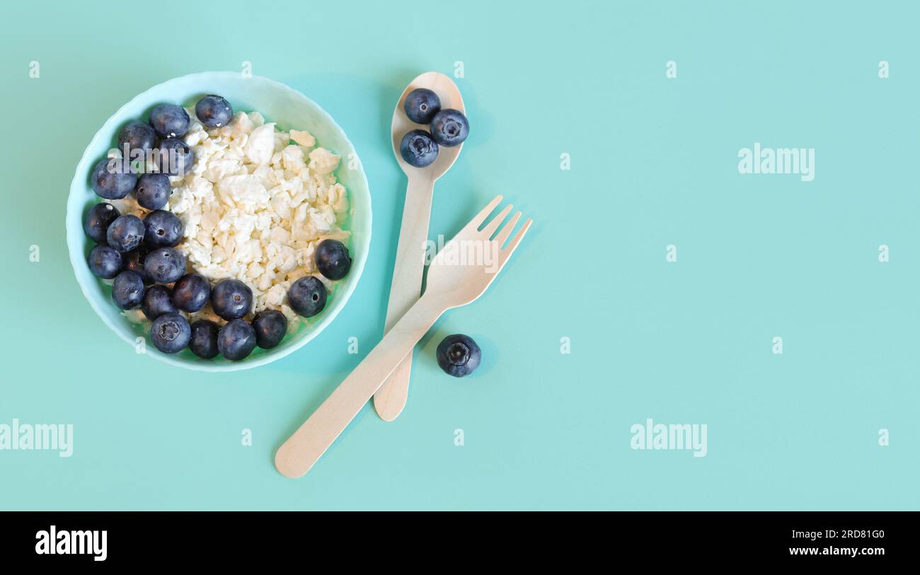 Deep plate with cottage cheese and blueberries on a turquoise ...
