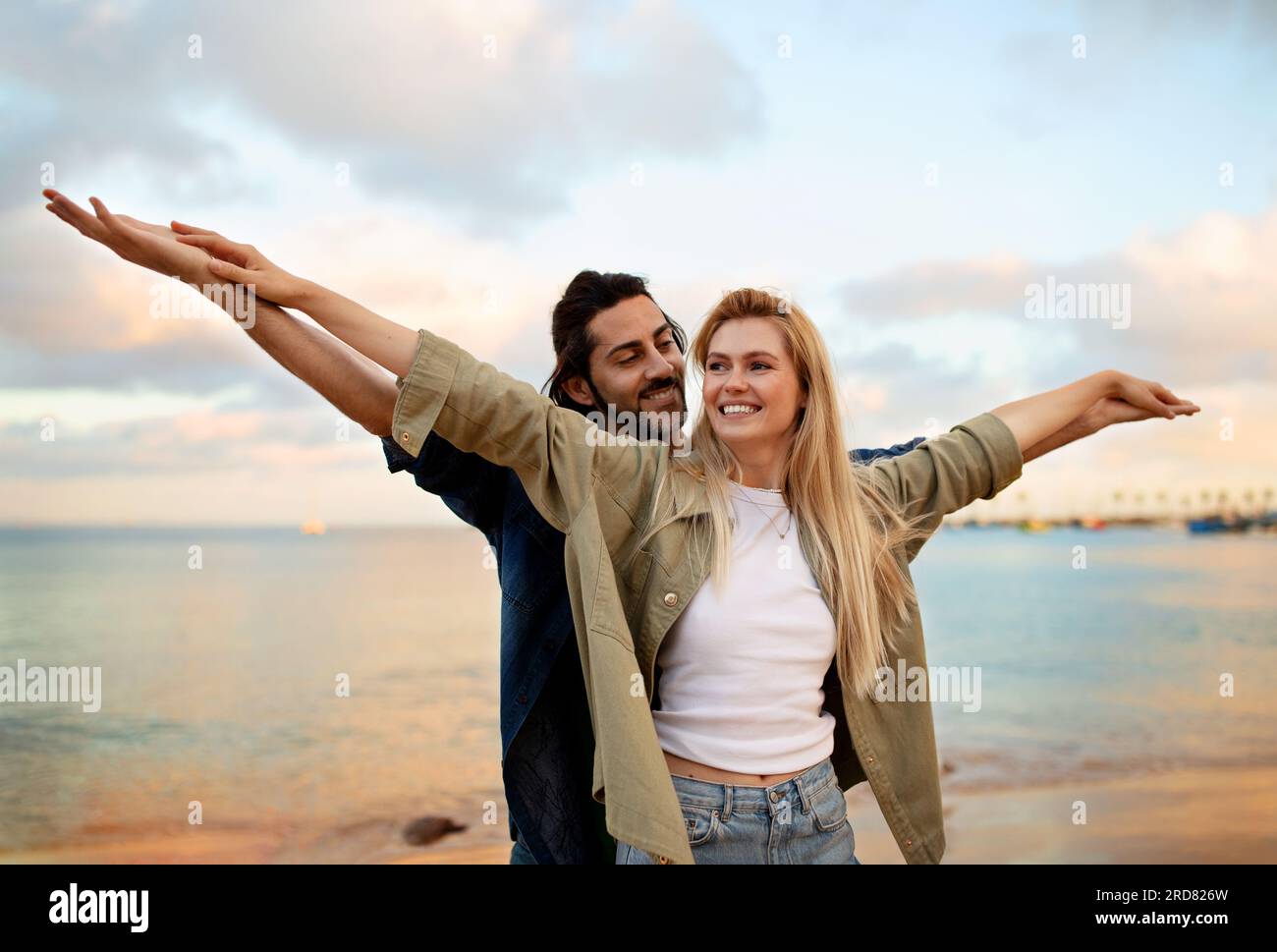 Let's fly. Joyful european couple having fun together at the beach ...