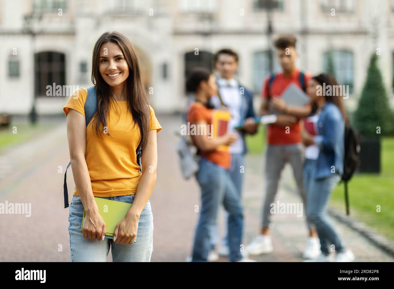 Student Life. Smiling young female posing in front college friends at ...