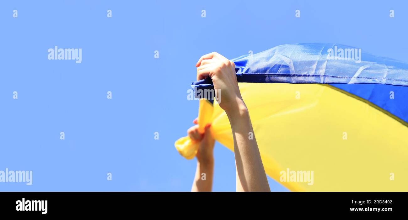 Yellow and blue flag of Ukraine in the woman's hands. Fluttering blue ...