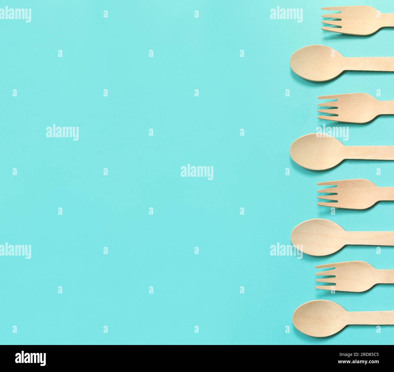 Wooden disposable forks and spoons on a blue background, top view. Eco ...