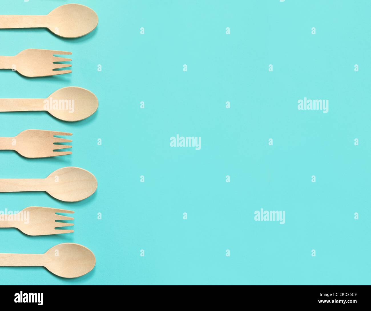 Wooden disposable forks and spoons on a blue background, top view. Eco ...