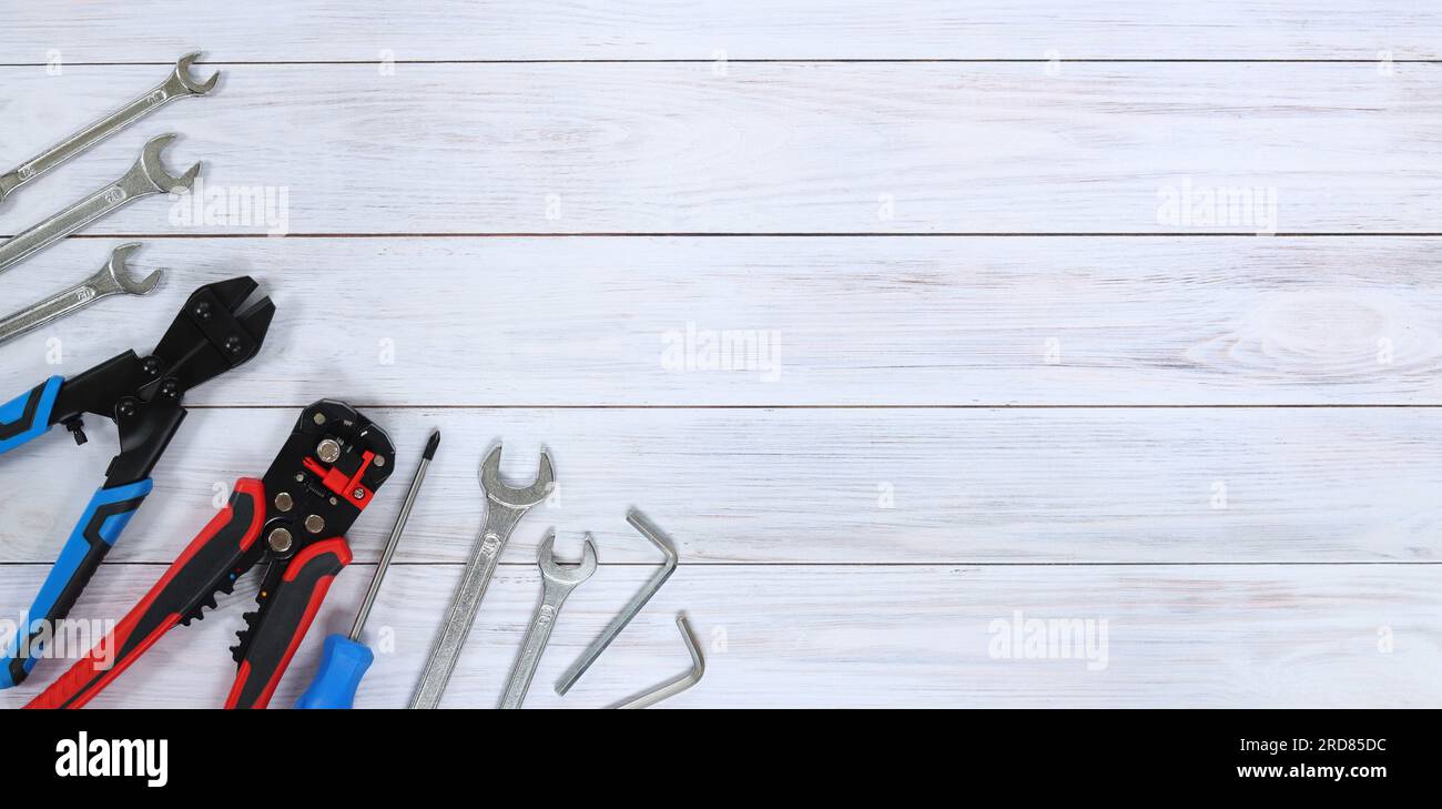 Repair tools on a wooden table, top view. Bolt cutter, wire stripper ...