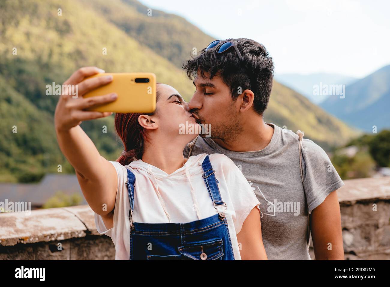 Lovely couple kissing and taking a selfie with mobile phone while doing ...