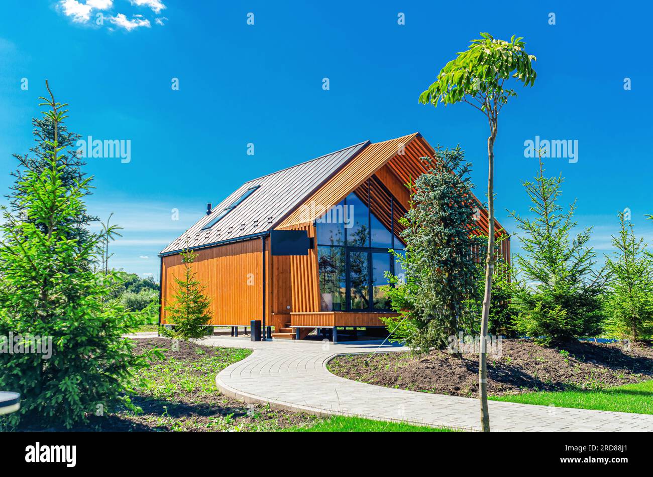 A small barnhouse house on a plot with a path, trees and bushes under a ...