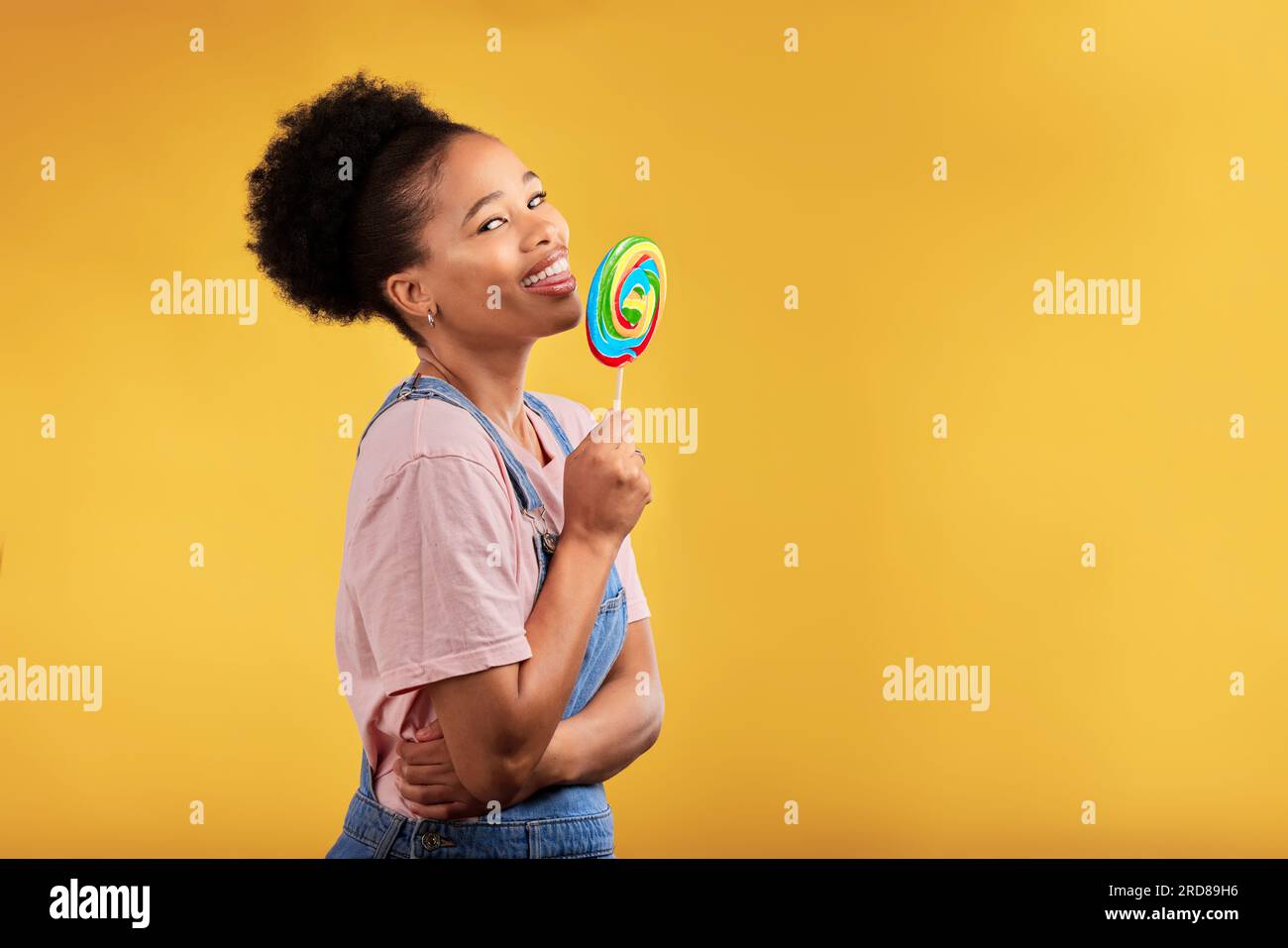 Black woman, portrait and eating candy or lollipop in studio on yellow ...
