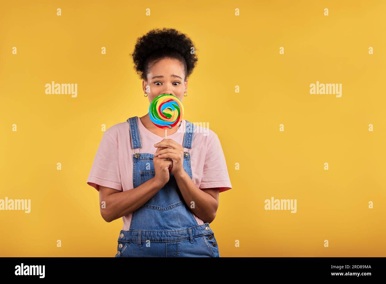 Black woman, portrait with candy or lollipop in studio on yellow ...