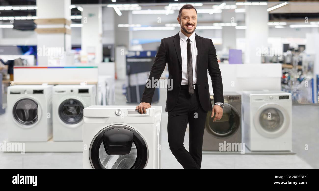 Man in a suit leaning on a washing machine inside a shop Stock Photo ...