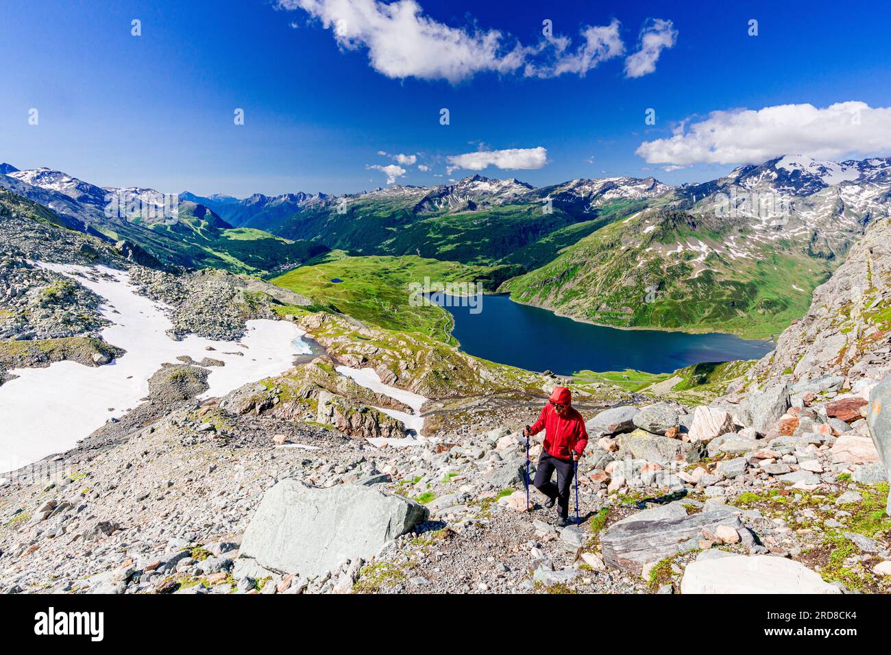 Hiker walking on mountain ridge above the blue lake Montespluga ...