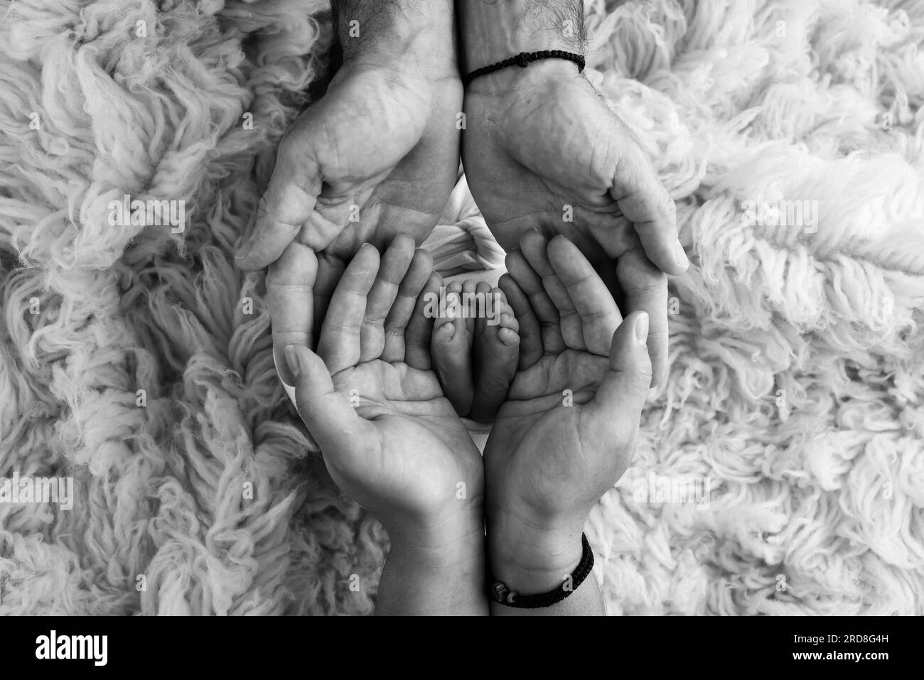 The palms of the father and mother are holding the foot of the newborn ...