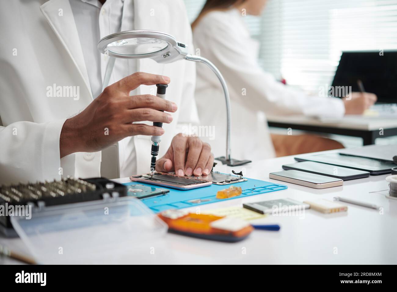 Technician looking through magnifying glass when reassembling broken ...