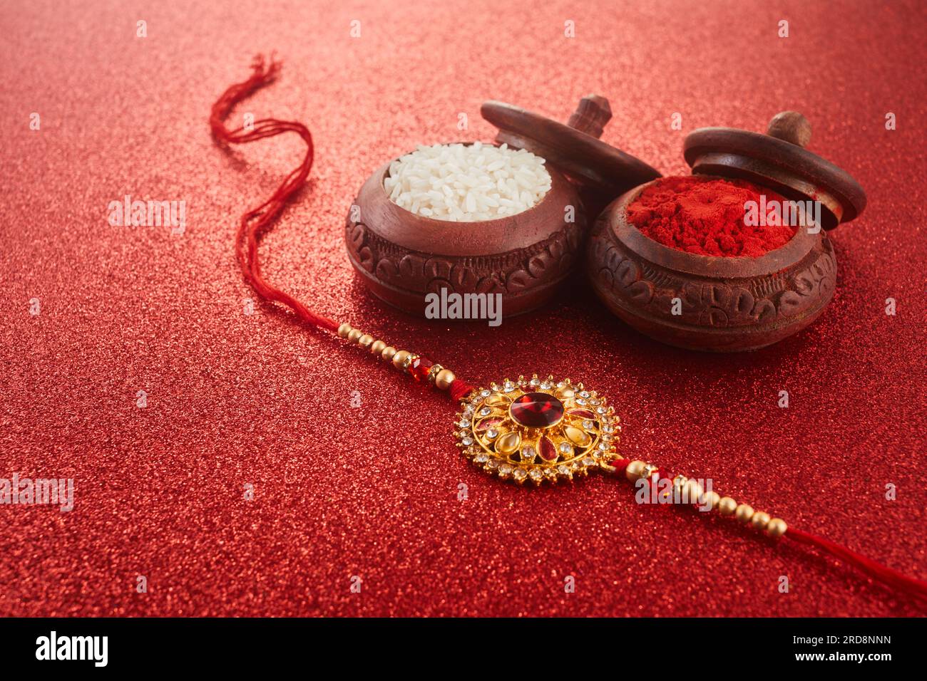 Raksha Bandhan. Rakhi string, Rice Grains and Kumkum on red background ...
