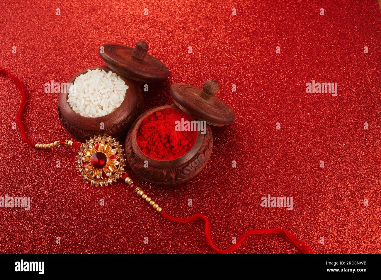 Raksha Bandhan. Rakhi string, Rice Grains and Kumkum on red background ...