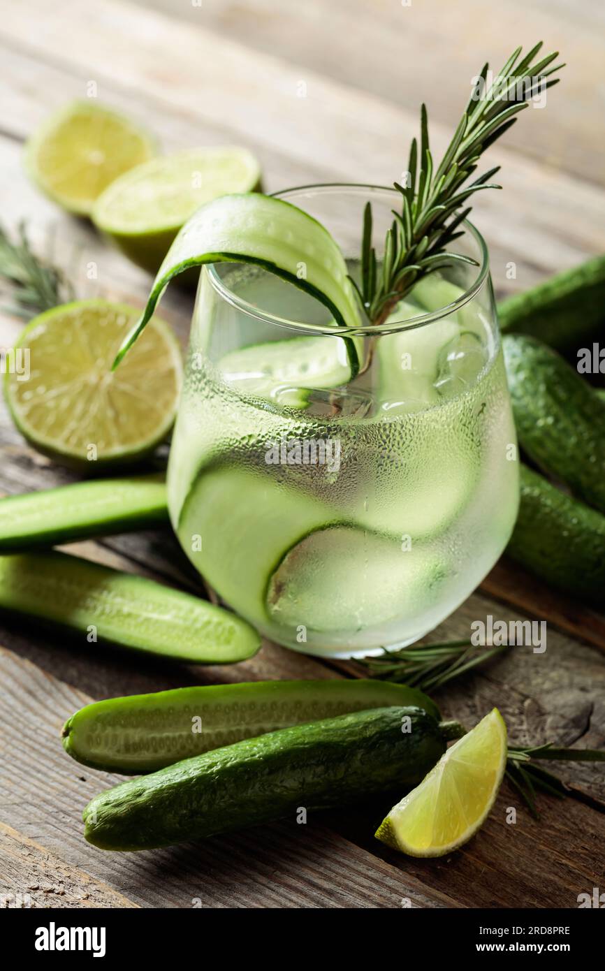 Gin tonic with ice, rosemary, lime, and cucumber slices in frosted ...