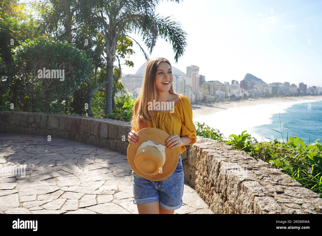 Portrait of happy cheerful Brazilian girl holding straw hat on lookout ...