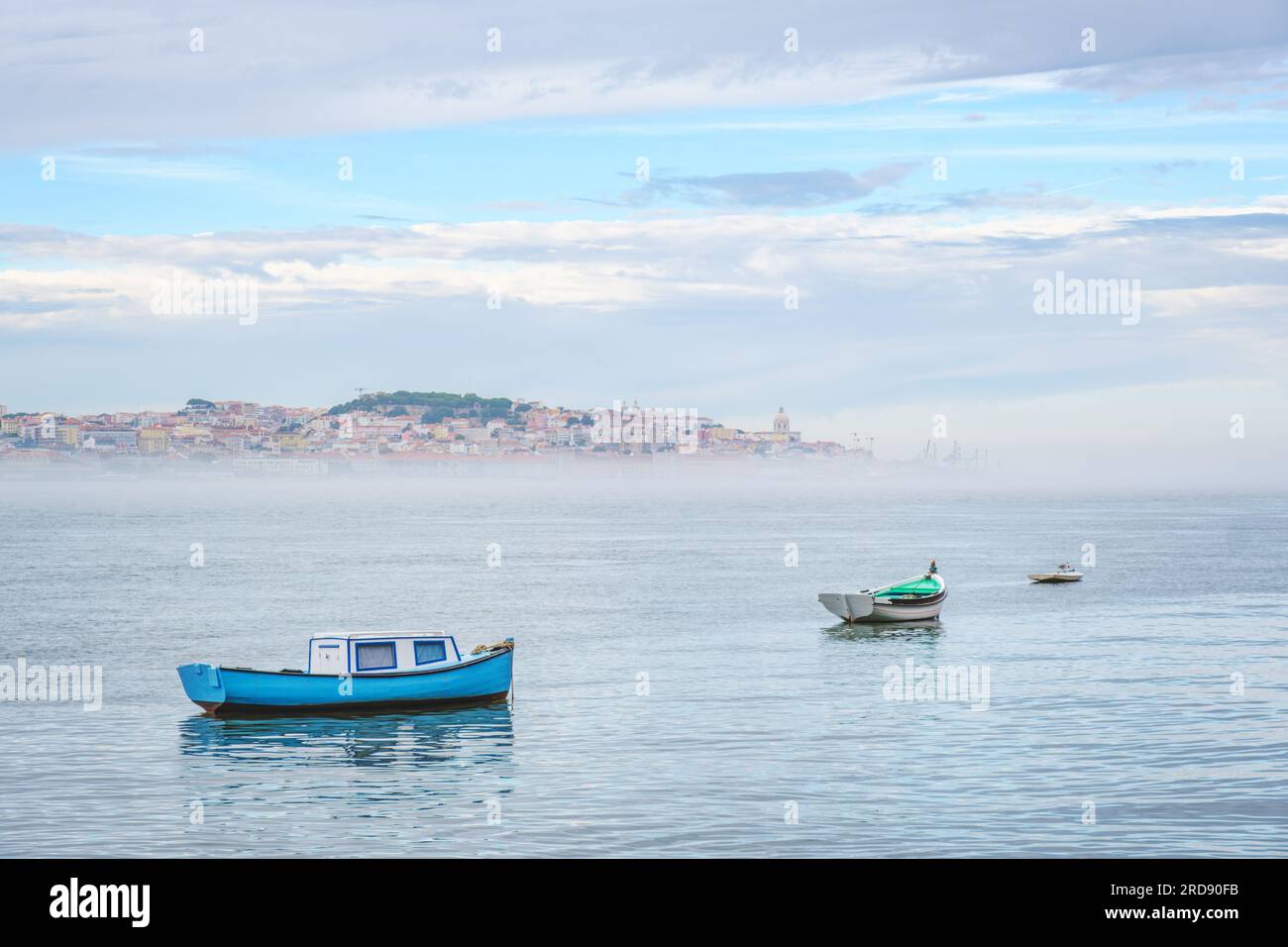 Boats in Tagus river on misty morning with Lisbon in background with ...