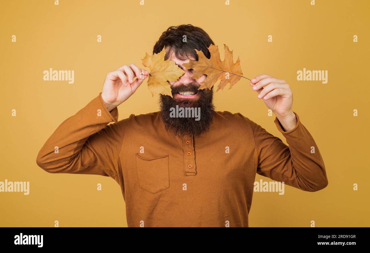 Fashion trends for fall. Smiling autumn man covered eyes with autumnal ...