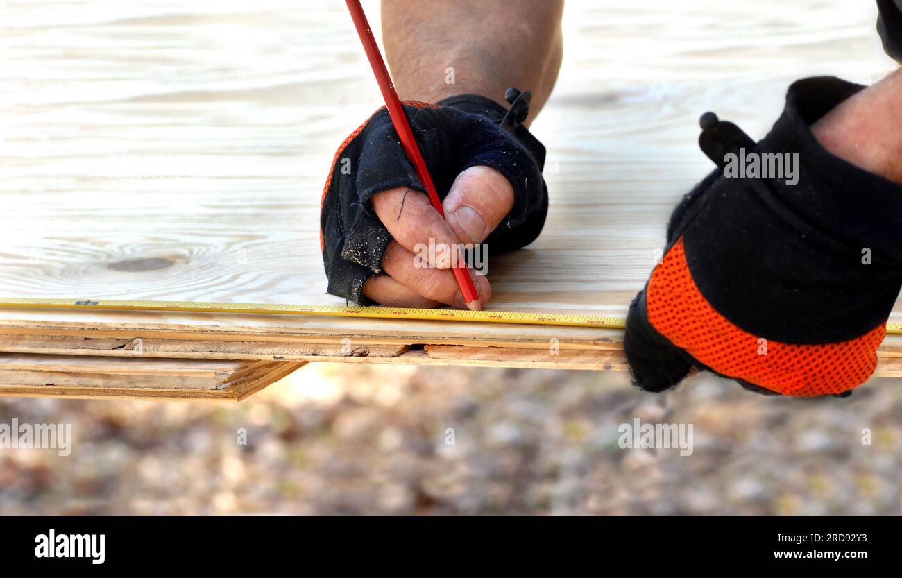 Carpenter makes marks using his tape measure to know the exact place to ...