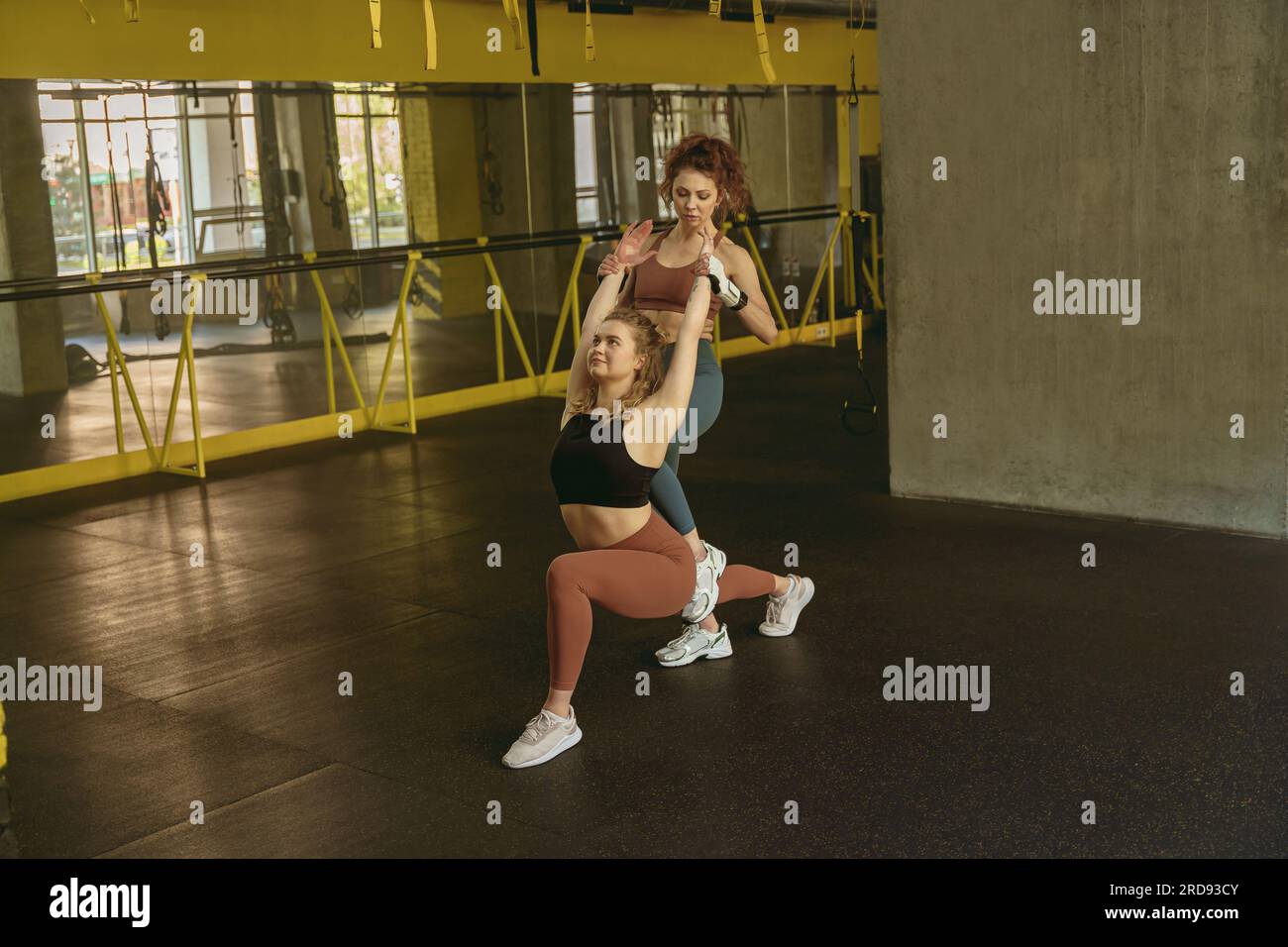 Fit young woman doing stretching exercises with the help of personal ...