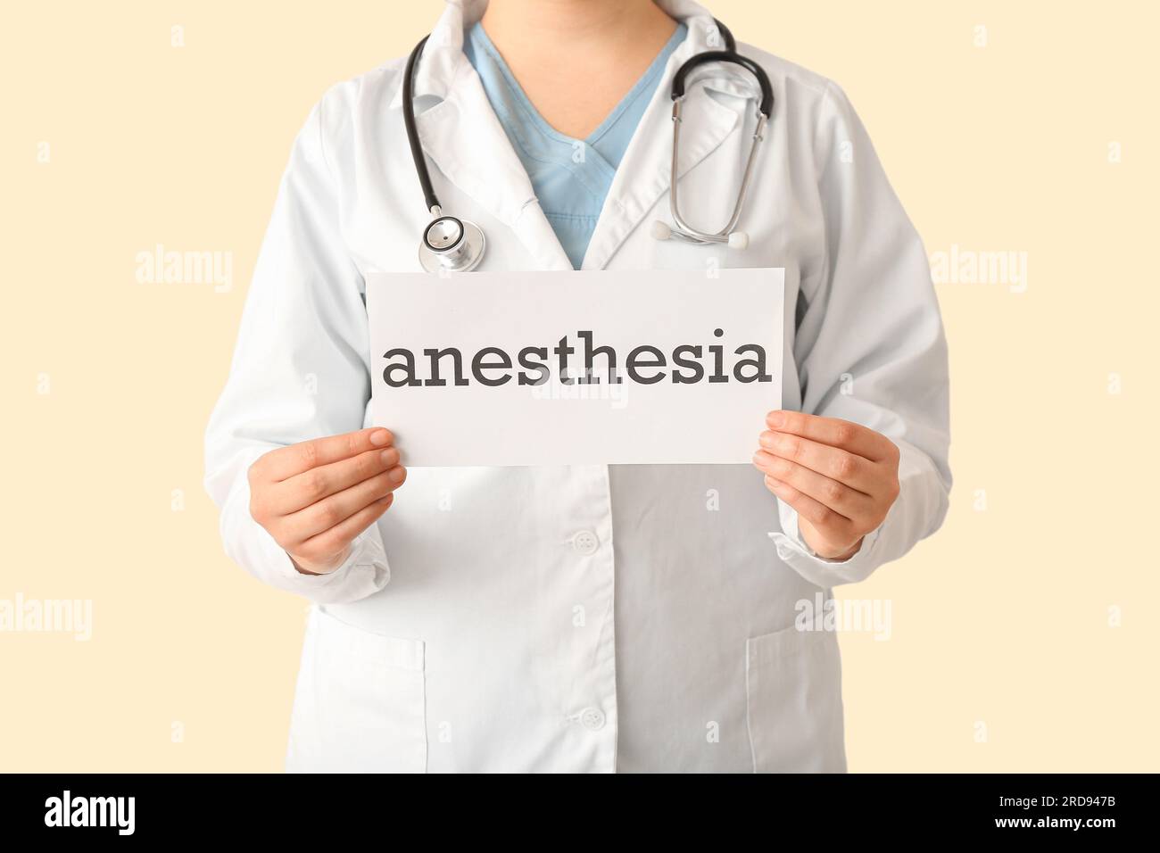 Female doctor holding paper with word ANESTHESIA on beige background ...