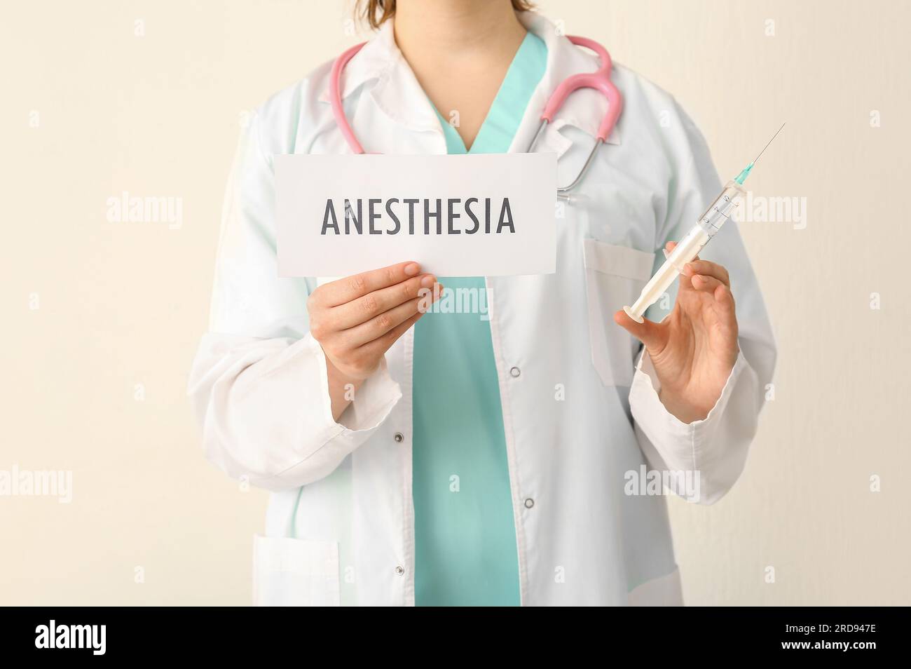 Female doctor holding paper with word ANESTHESIA on beige background ...