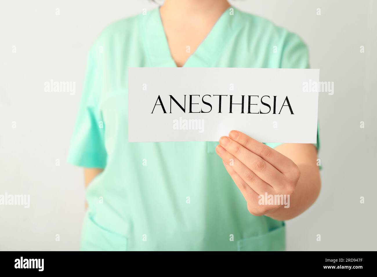 Female doctor holding paper with word ANESTHESIA on light background ...