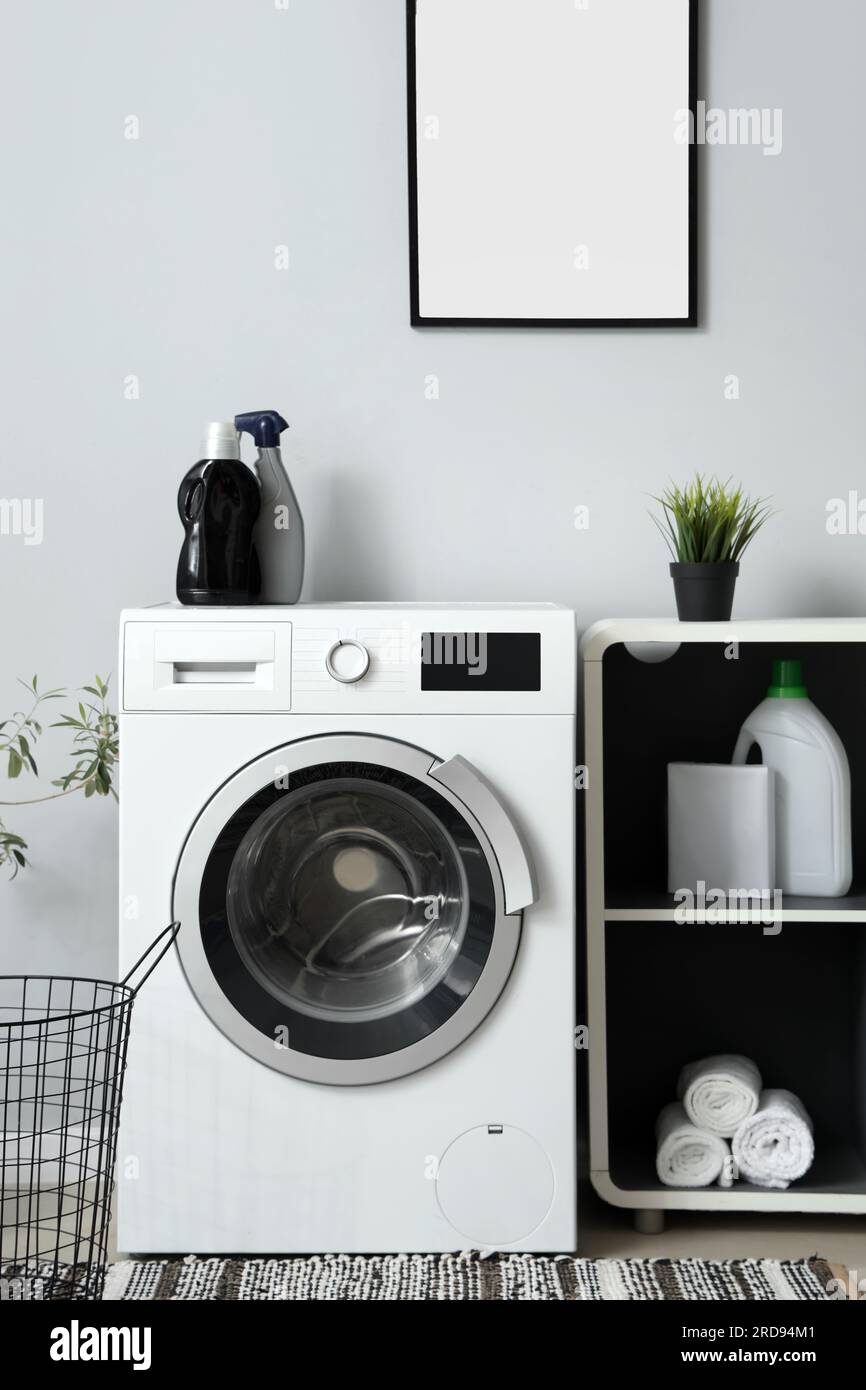 Washing machine and shelving unit with bottles of detergent near grey ...