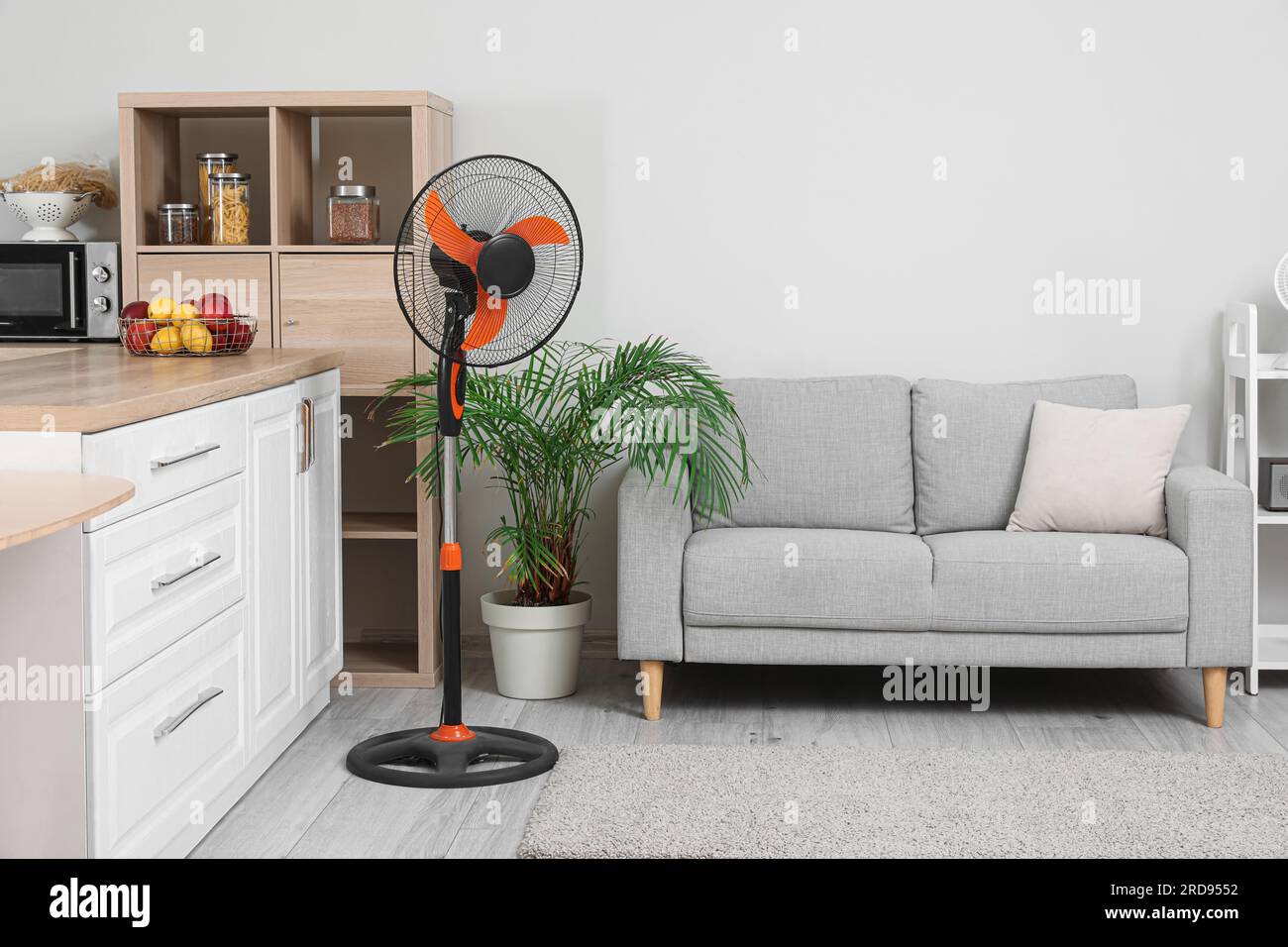 Interior of light living room with grey sofa and modern floor fan Stock ...