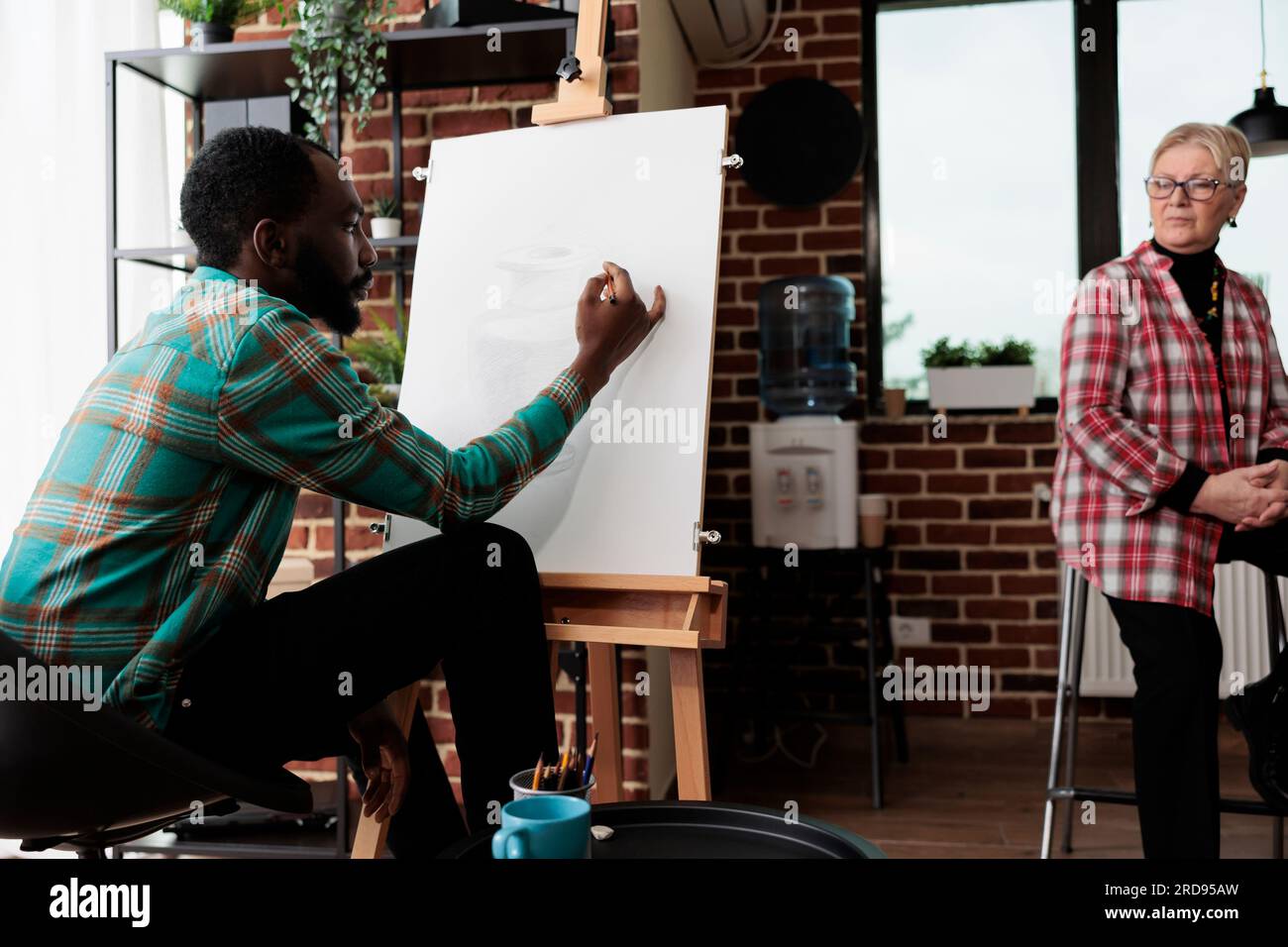Young focused African American guy learning to draw with teacher, male ...