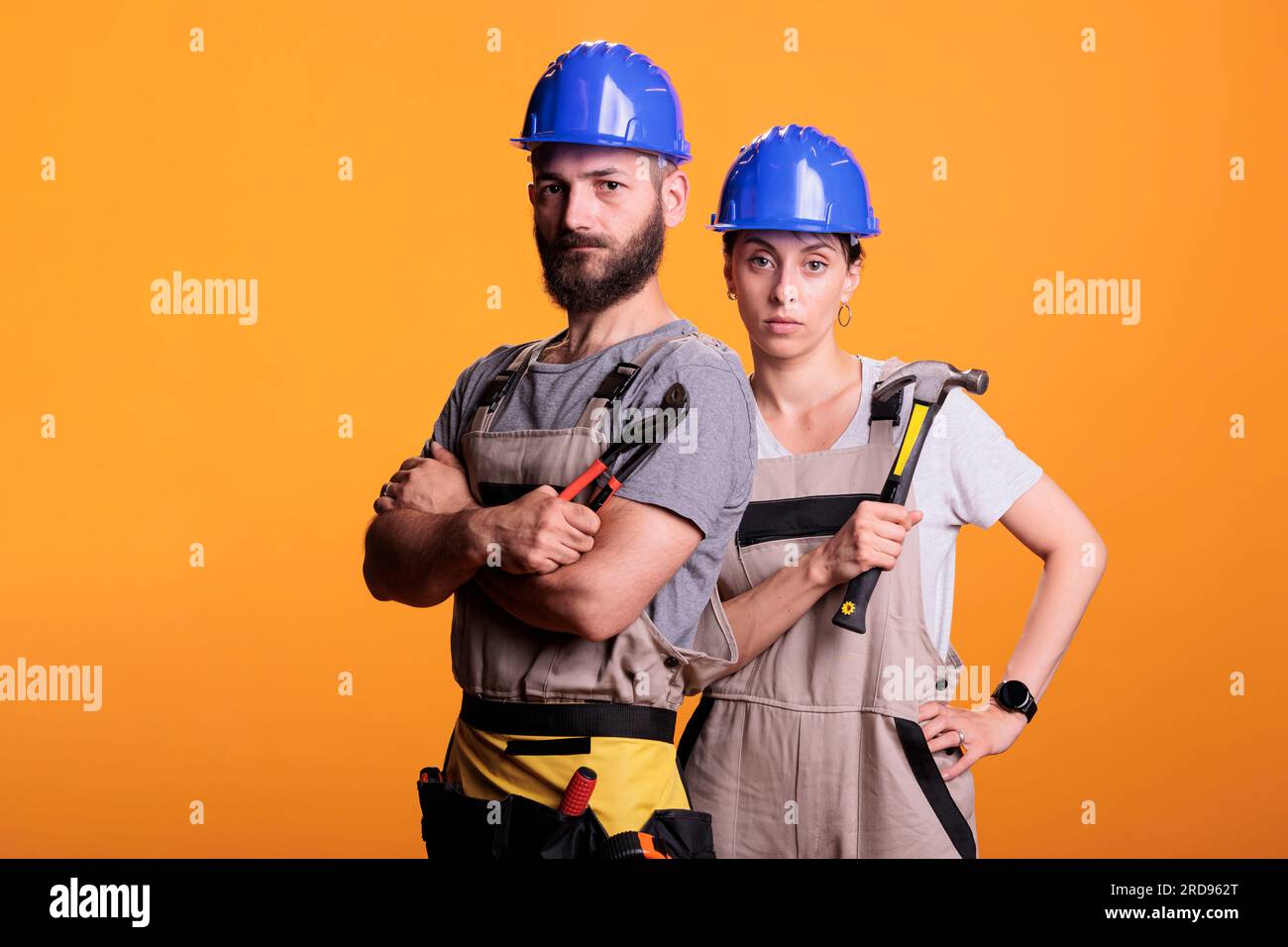 Serious construction workers posing with pair of pliers and hammer ...